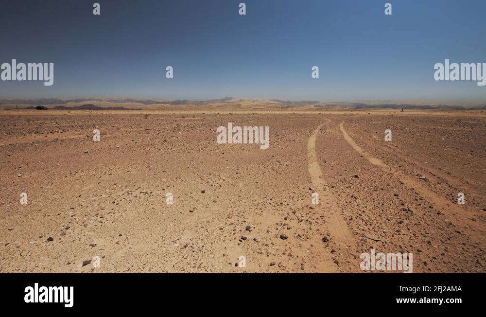 Black car cross the vast Wadi Araba desert from left to right in Jordan ...