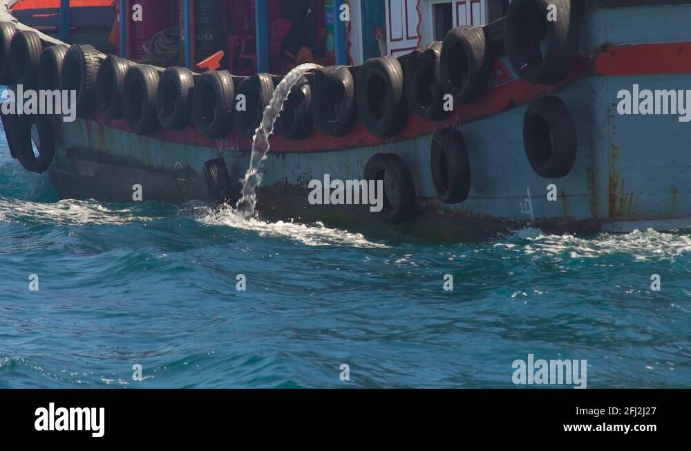 Ship floating with car tires on board drain water in blue sea. Floating ...