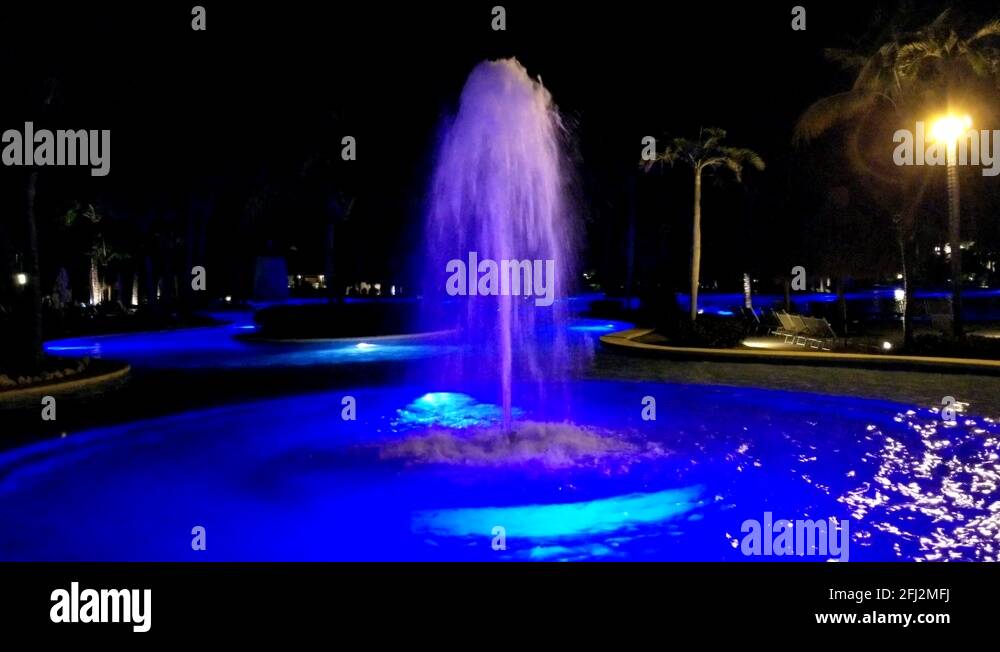 Swimming Pool Fountain shoots water high entertaining people at night ...