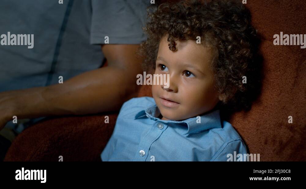 Close up of a smiling little boy at the movie theatre enjoying the film ...
