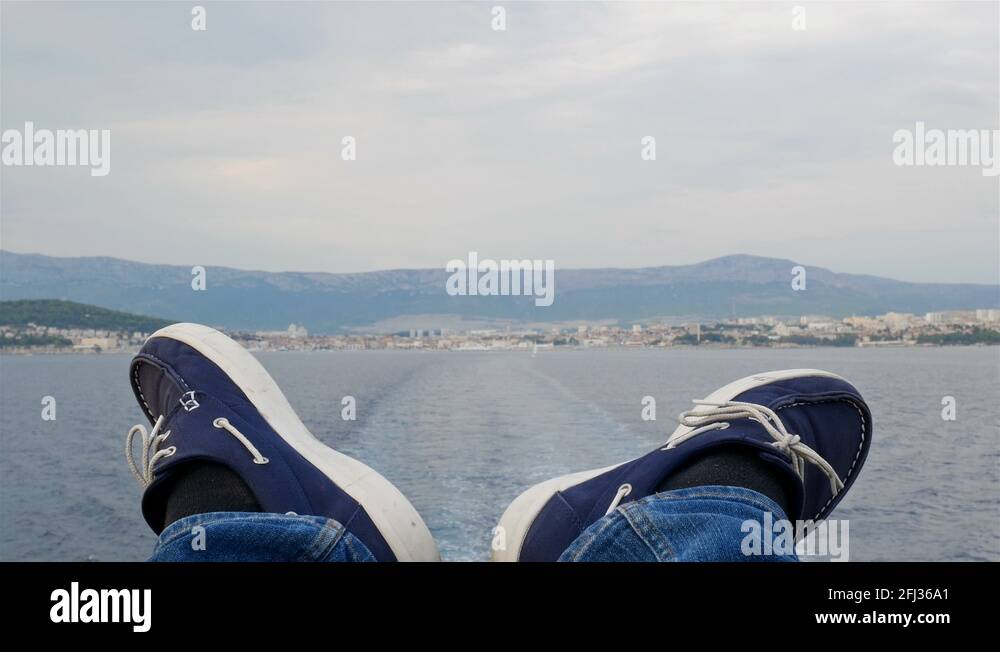 Man legs on cruise boat rear end with city Split in Croatia at ...