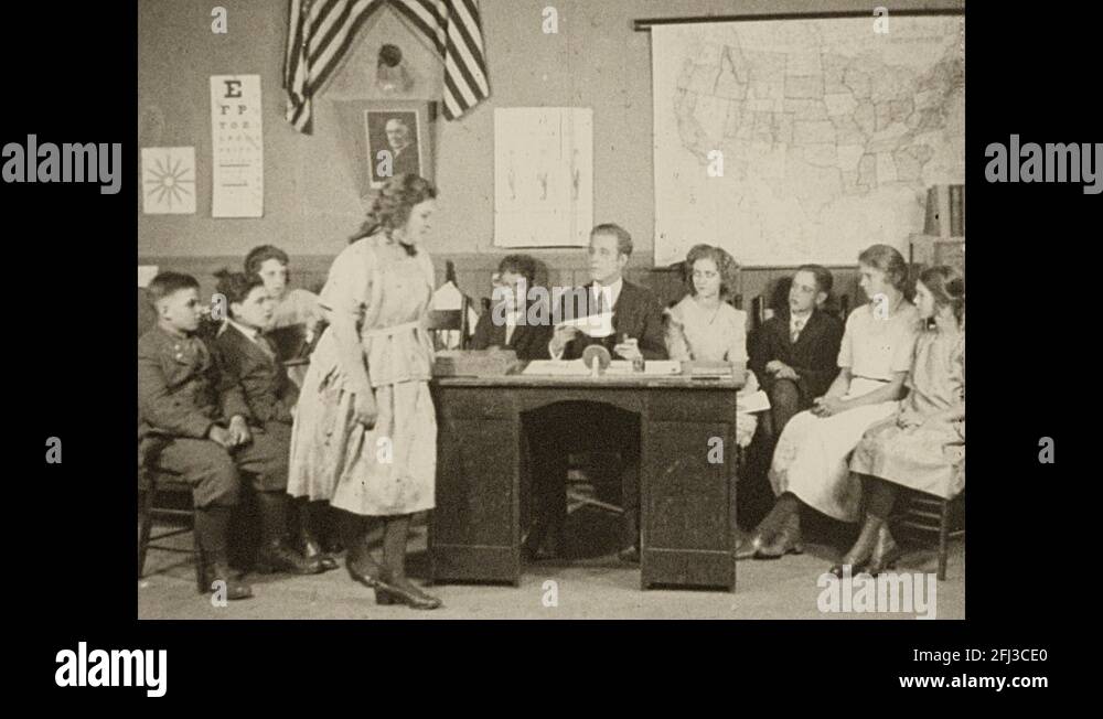 1930s: A man sits at a desk in a classroom, surrounded by students. A ...