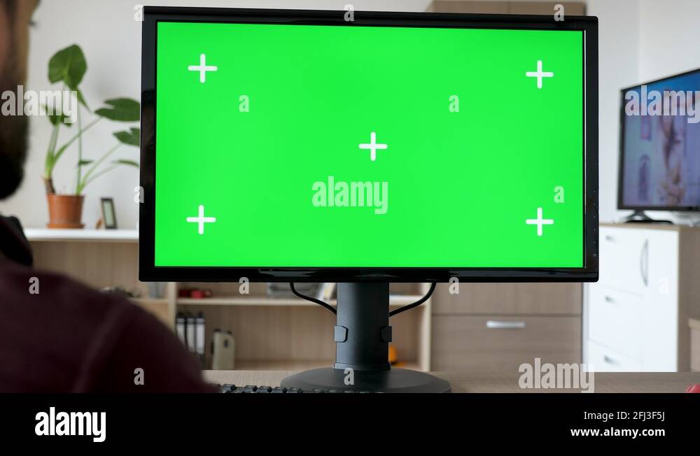 Unrecognisable man looking at modern personal computer with big green ...