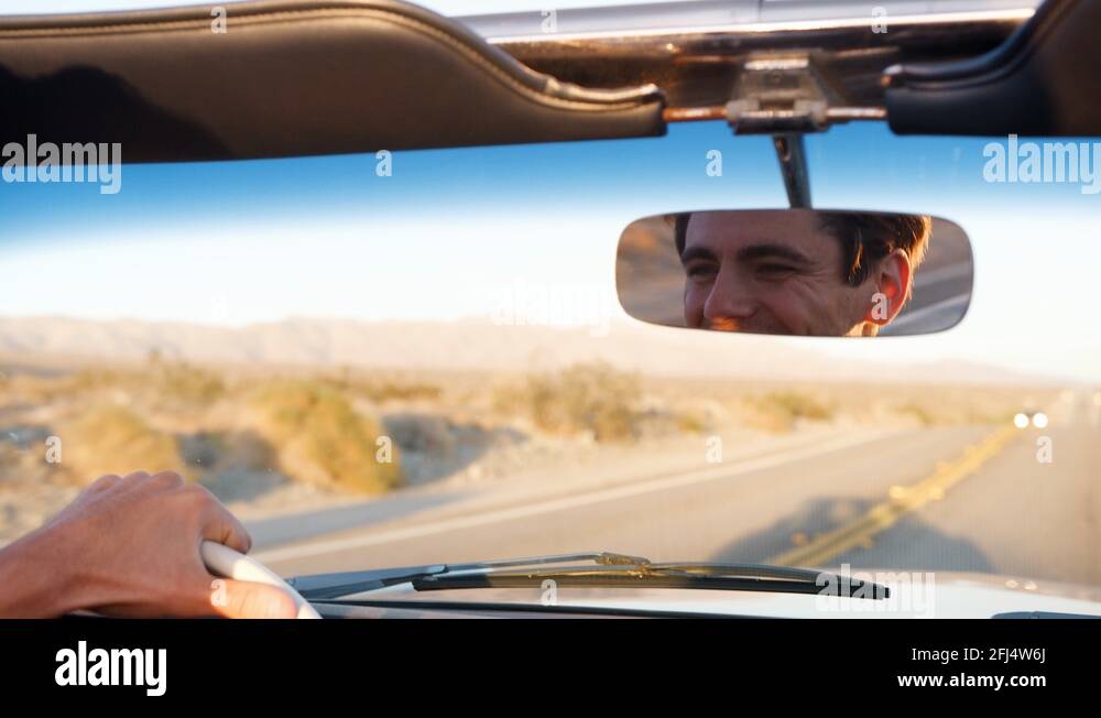 Young white man driving an open top car, face seen in mirror Stock ...