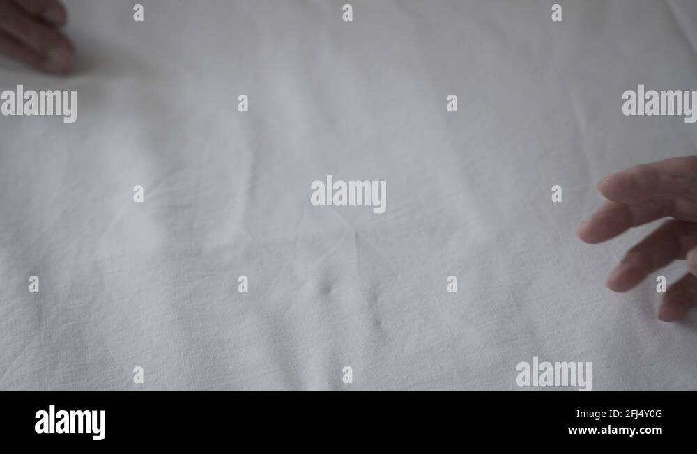 Old senior hands coming together in a gentle handshake on a white cloth ...