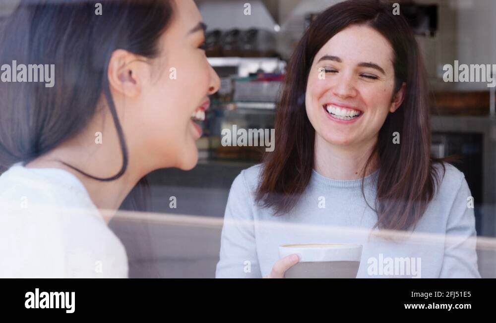 Female friends laughing in coffee shop, seen through window Stock Video ...