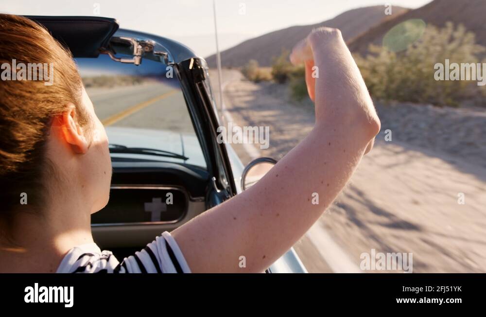 Woman in the front passenger seat of open top car, back view Stock ...