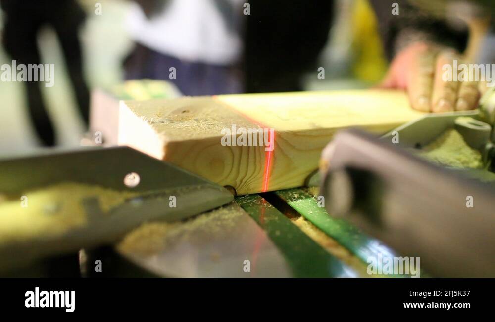 A close-up of a person using a power miter saw, while cutting wooden ...