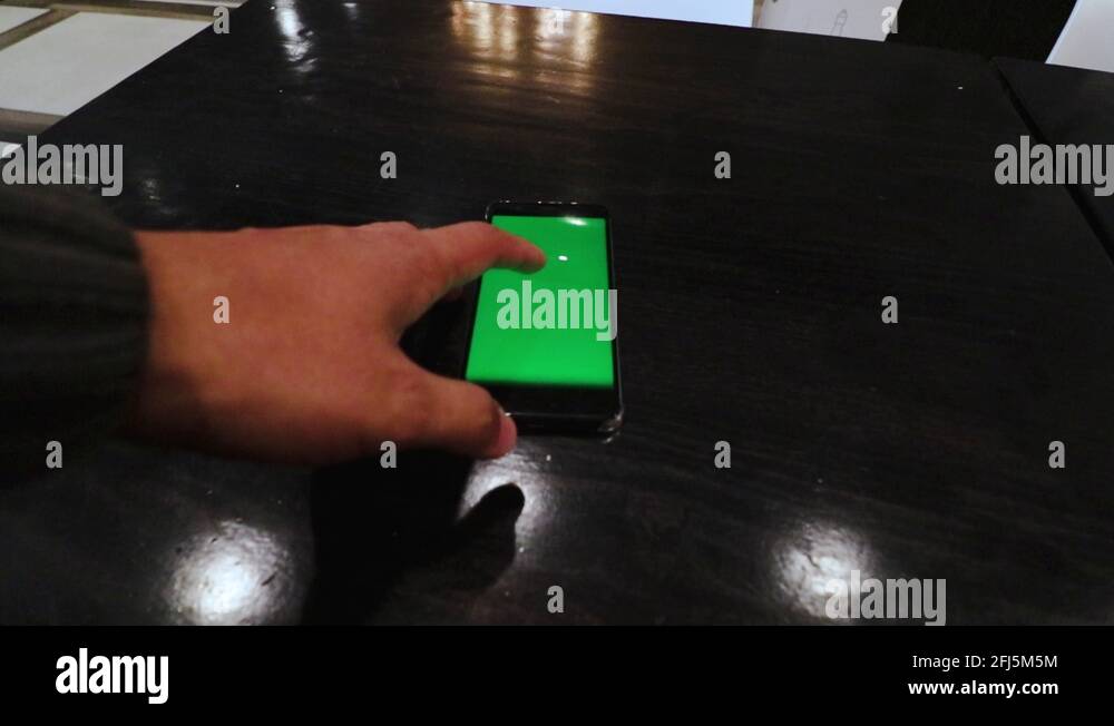 Using a cell phone, typing a number with green screen on a talbe Stock ...