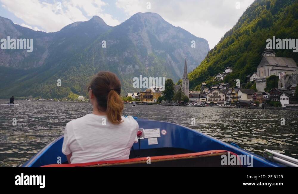 young woman riding boat enjoying view of famous village Hallstatt ...