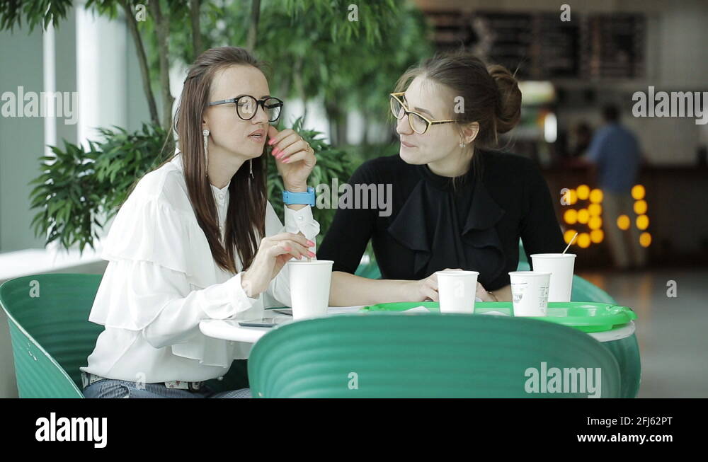 Coffee break two business women in the cafeteria. Business talk over a ...
