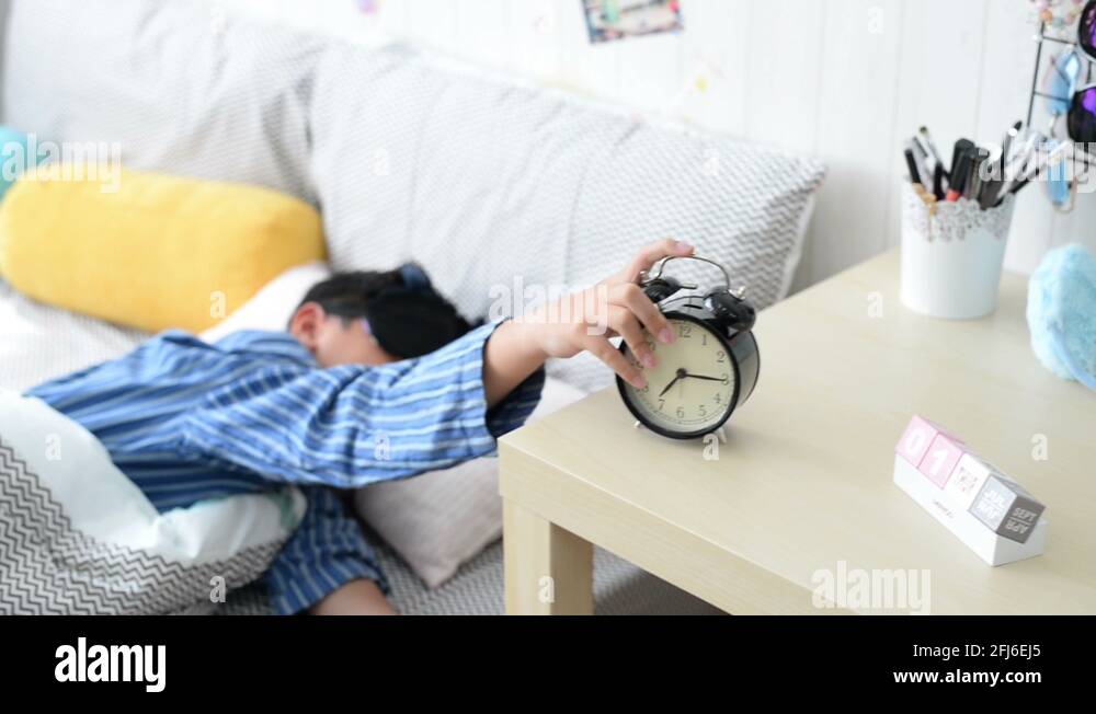 Young asian boy sleeping and turn off alarm clock falls out of bed ...