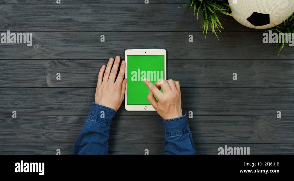 Top view on the white vertical tablet device with green screen in hands ...