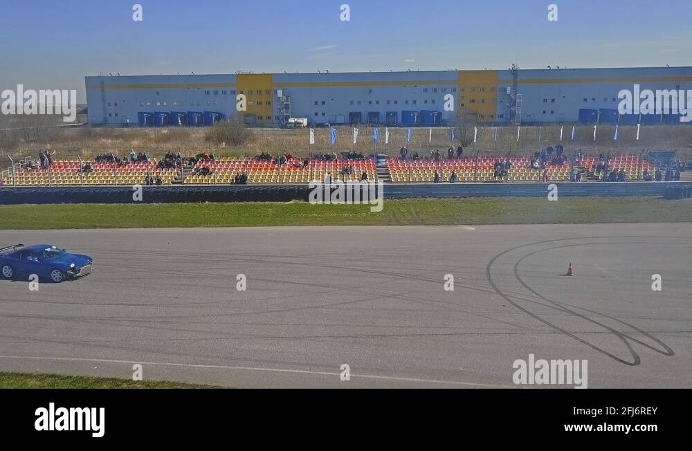 Blue race drifting car finishing a track lap with viewers and finish ...