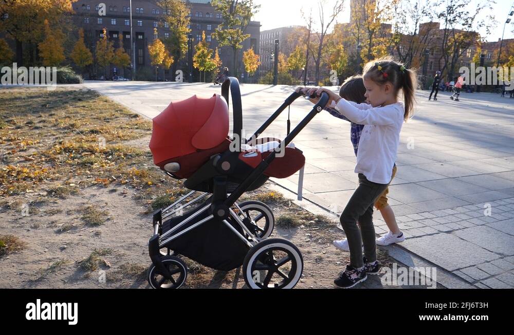 Brother and sister children pushing together the stroller with baby ...