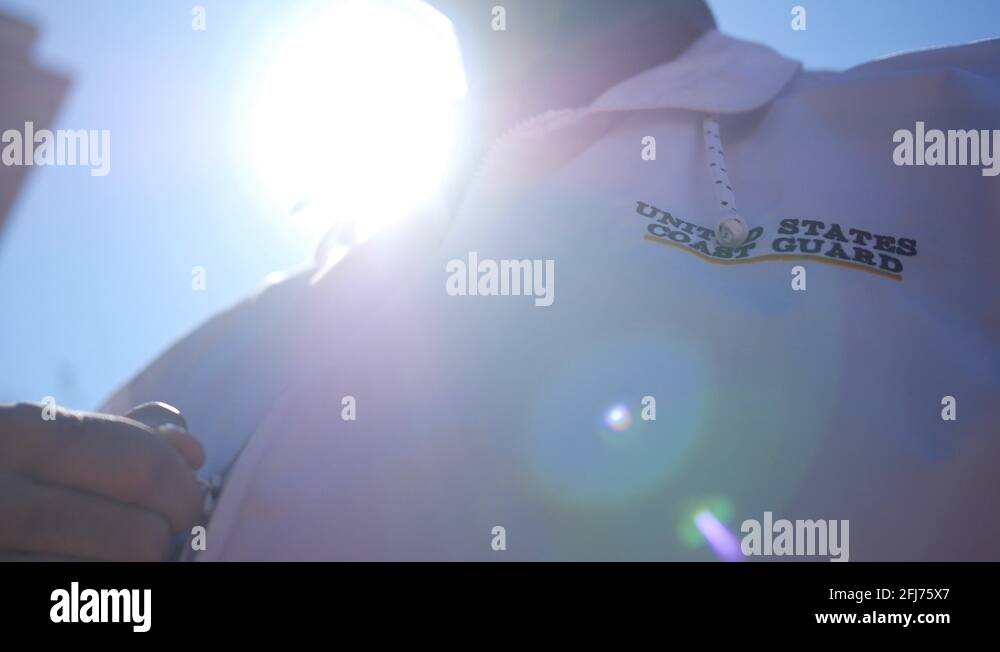 A Coast Guard officer zips up his jacket dramatically with sunset lens ...