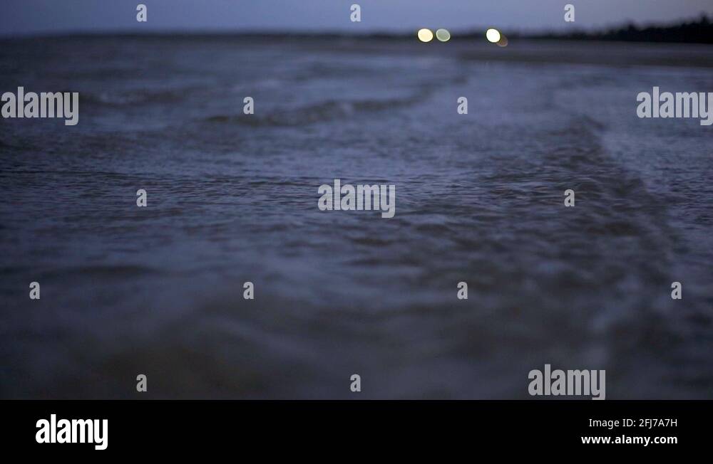 Small Choppy Waves at Ankle Deep Level. Shoreline in Sight, with Lights ...