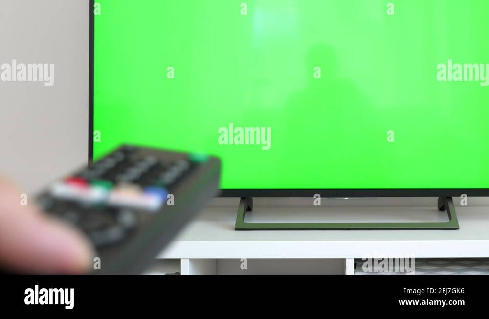 Watching tv with green screen at home interior. Push buttons on remote ...