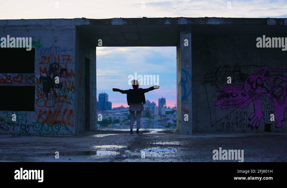 Woman raising hand in air on rooftop of abandoned building, street ...