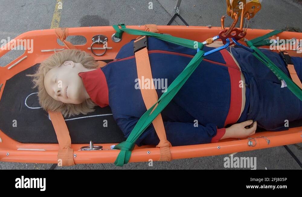 Blond training mannequin strapped into stretcher for demonstration to ...