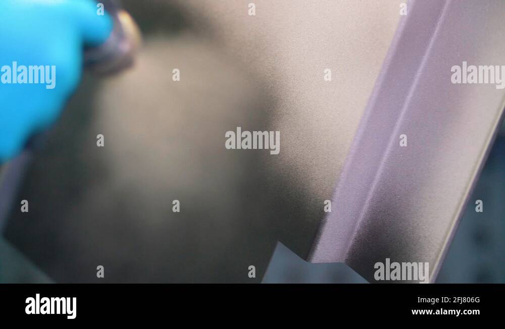 Man applying black anti-corrosion powder coating to metal sheet using a ...