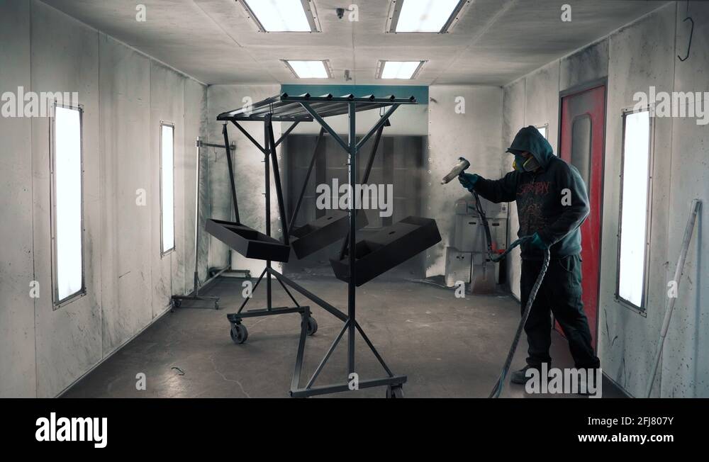 Man applying black anti-corrosion powder coating to metal sheet using a ...