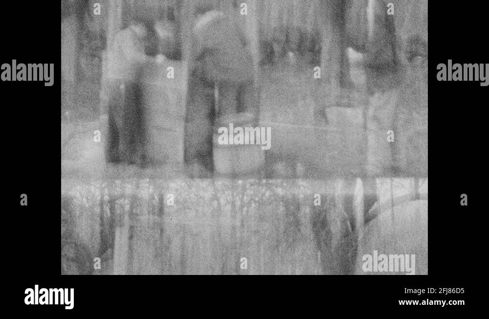 1930s: Children pull rope and draw water bucket from well in yard ...