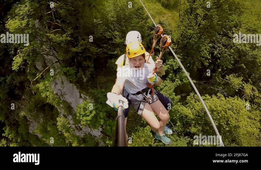 Two people in tandem canopying over the forest on zipline in Slovenia ...