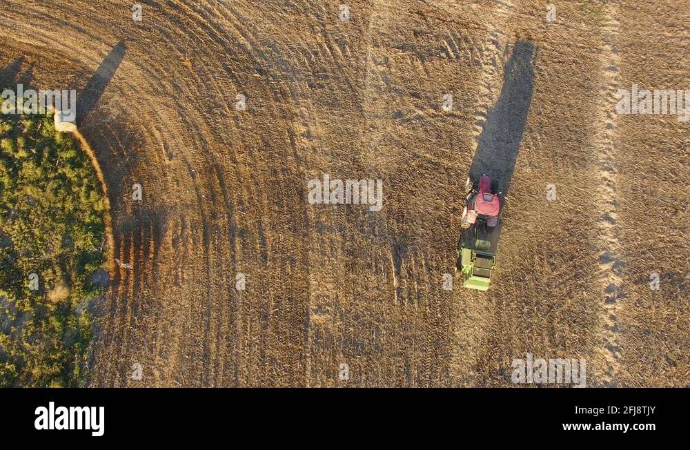 A baling machine opens and unloads a large round bale into a field ...