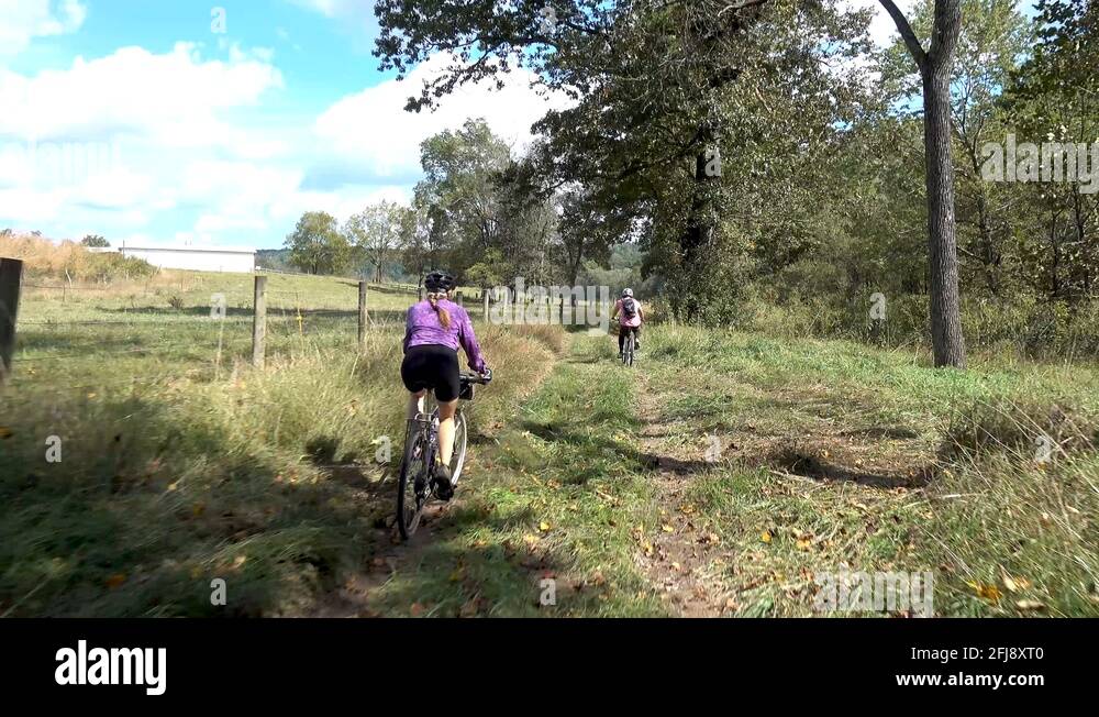 Following behind a woman on a mountain bike on a dirt jeep track with ...