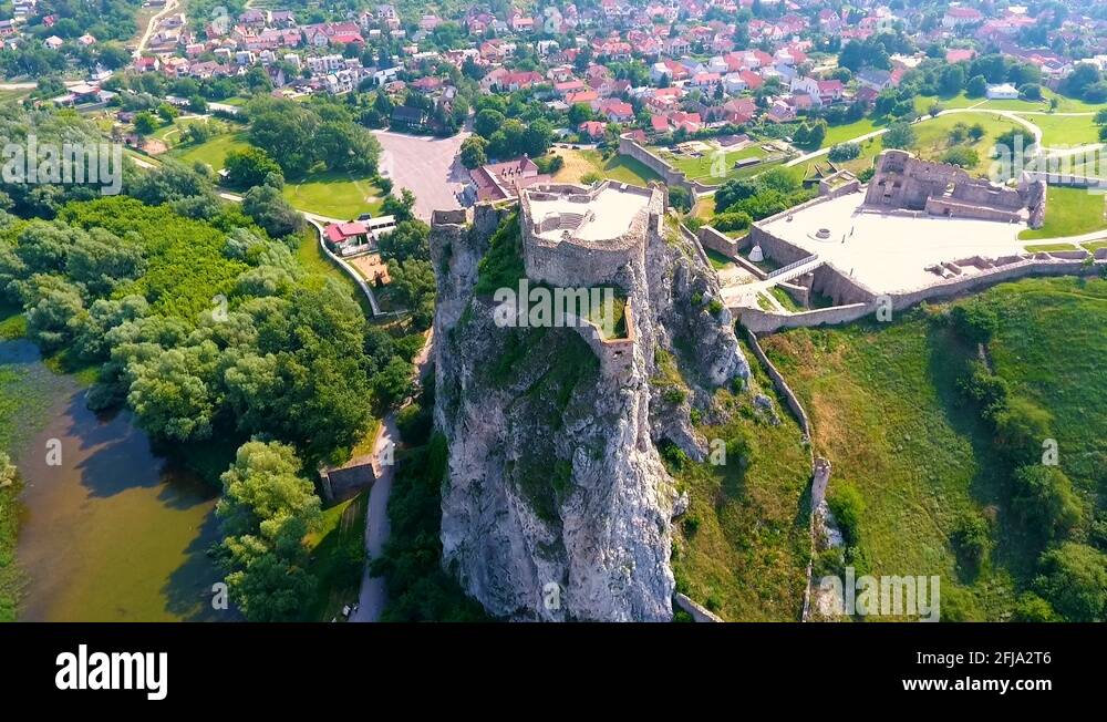 Drone footage of ruined castle on top of a hill with river and village ...