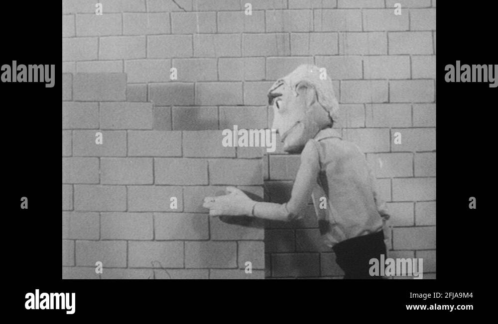 1960s: Puppet man builds brick wall. Puppet man stands next to brick ...