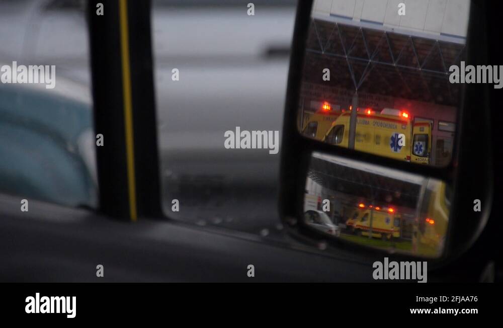 View of an ambulance with flashing lights as seen through a rear view ...