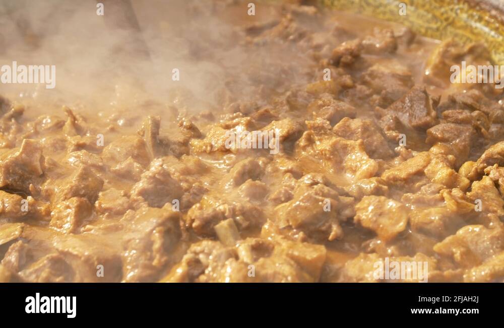 Shaking a cauldron full of boiling and smoking boar stew over fire ...