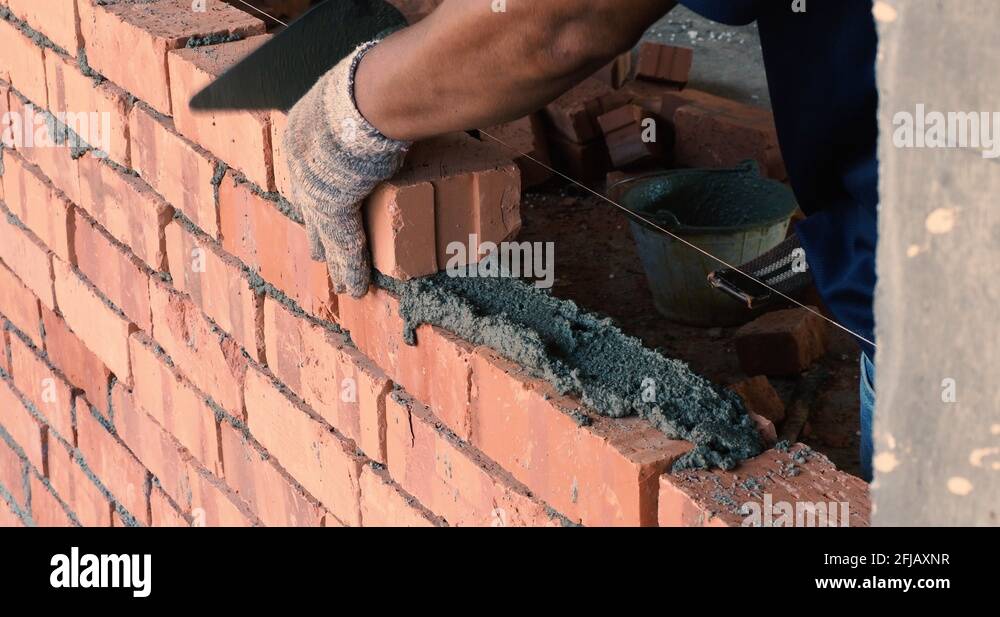 Asian Man laying Bricks on top of mortar to build wall Stock Video ...
