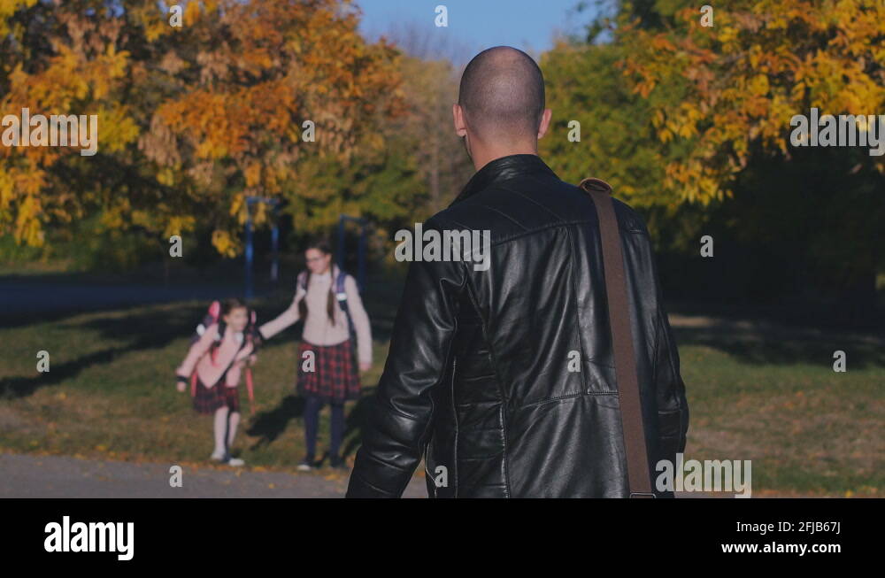 Young happy father meets his daughters from school. Two girls in school ...