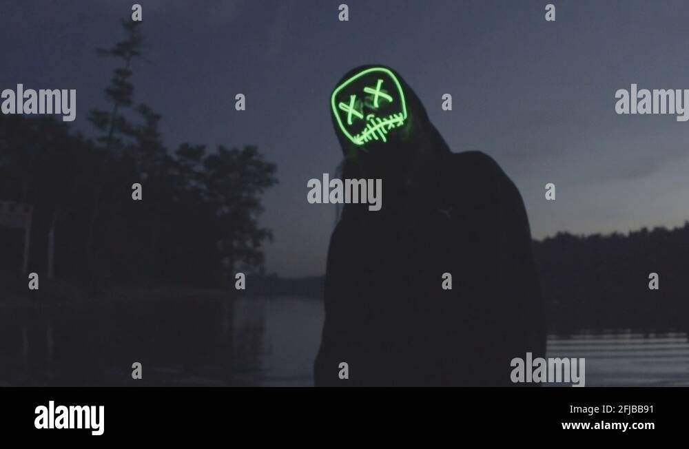 Mystery Girl wearing scary Green glow Halloween mask looks at camera at ...