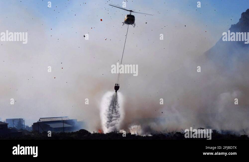 Helicopter drops water from bucket on fire hot embers cinemagraph ...