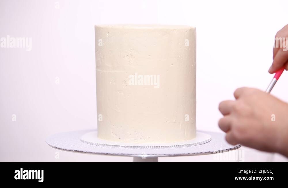 Applying glitter dust on tall birthday cake with white buttercream ...