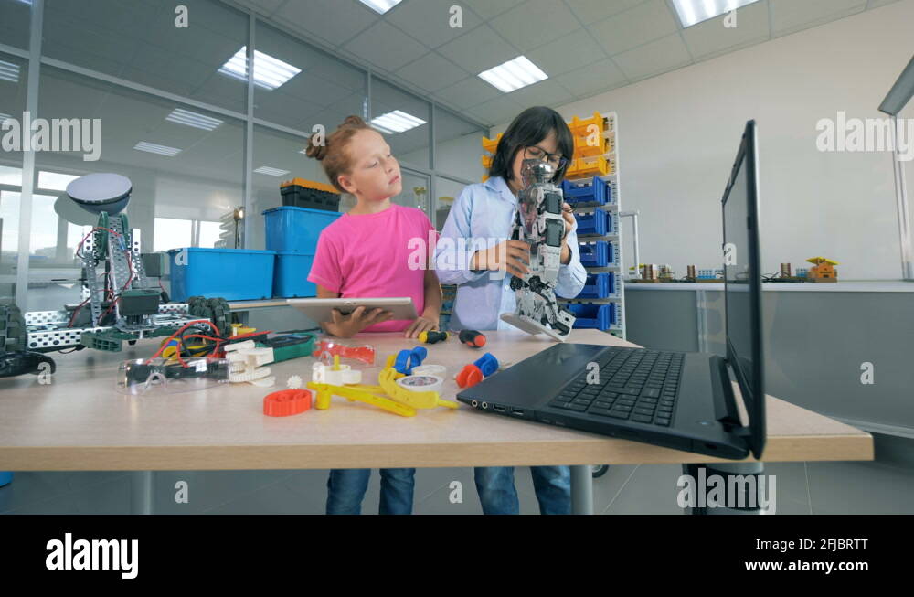 Two school kids construct a plastic robot in a school laboratory ...