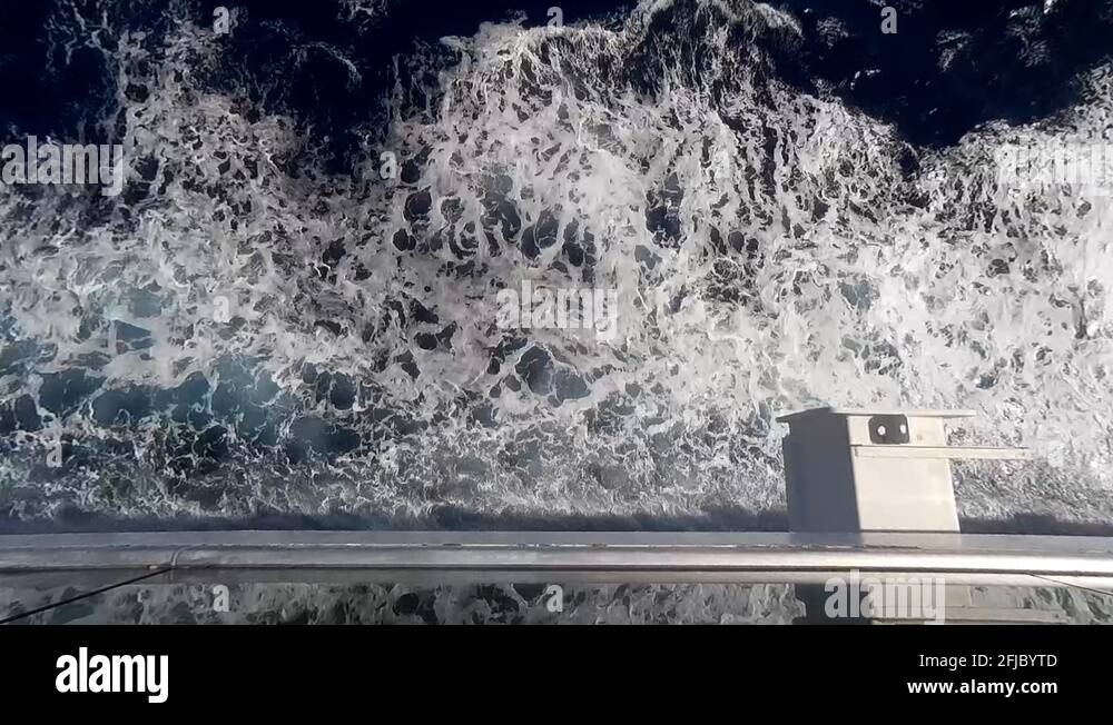 Over the side of a cruise ship looking down at it carving through the ...