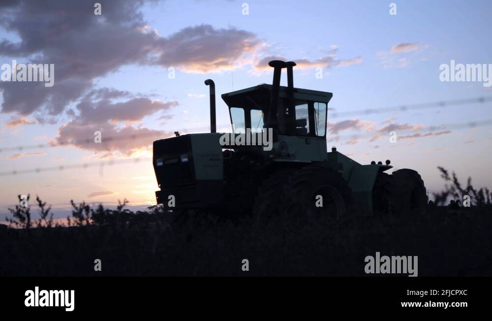 Slow sideways panningement while big old tractor starts up early in the ...