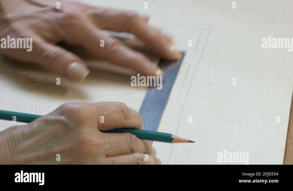 Seamstress ruler and pencil in hand is making drawings for clothes ...