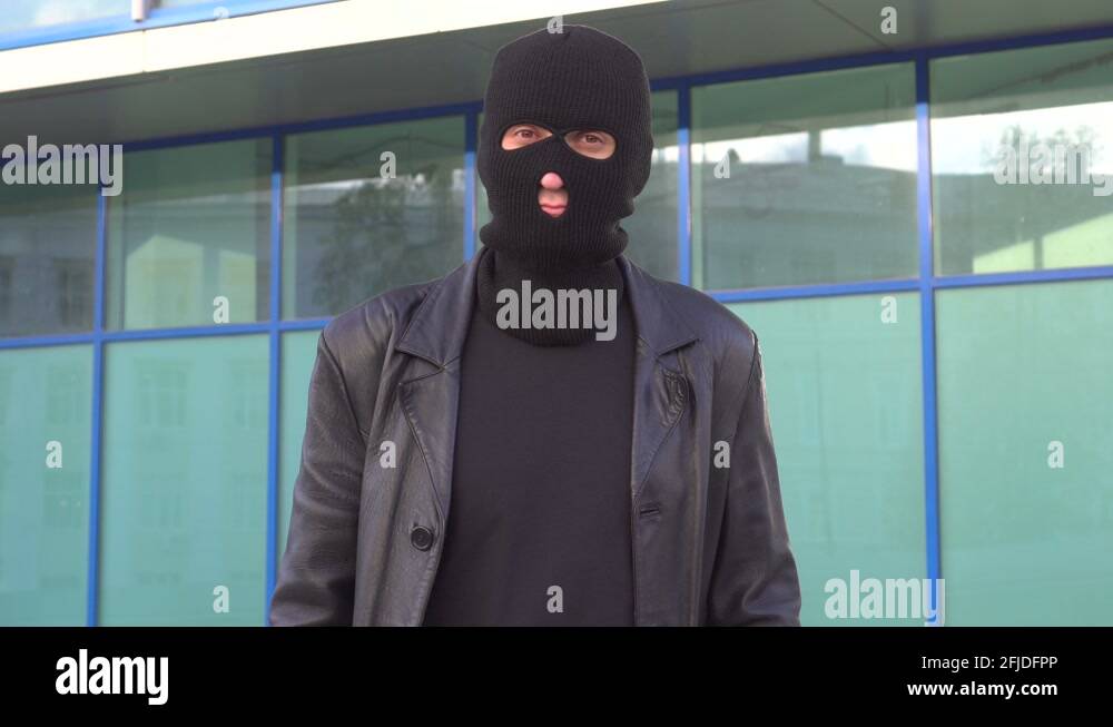 Man in the mask standing outdoor. Robber, bully, hoodlum, thug, ruffian ...