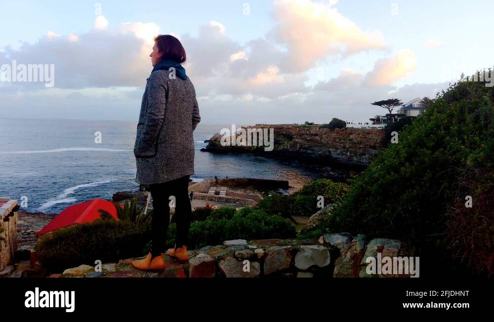 Women looking out over ocean at lookout point searching for whales in ...