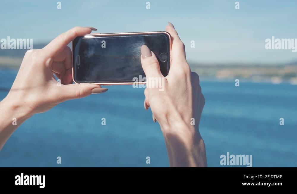 Back view of a woman taking photograph with a smart phone camera at the ...
