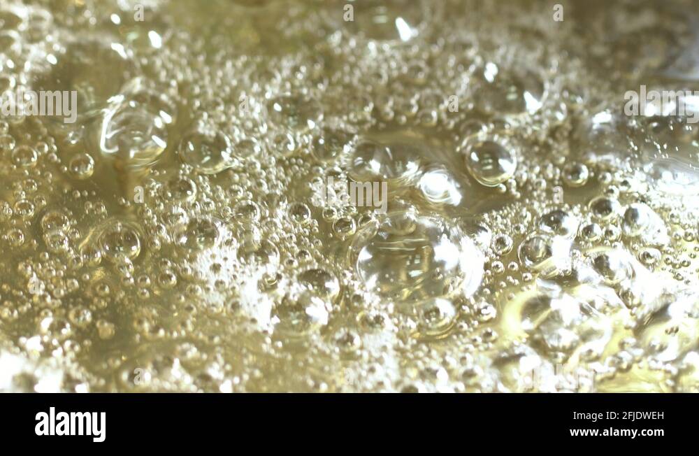 Boiling and bubbling sugar syrup and agar agar in a Teflon saucepan on ...