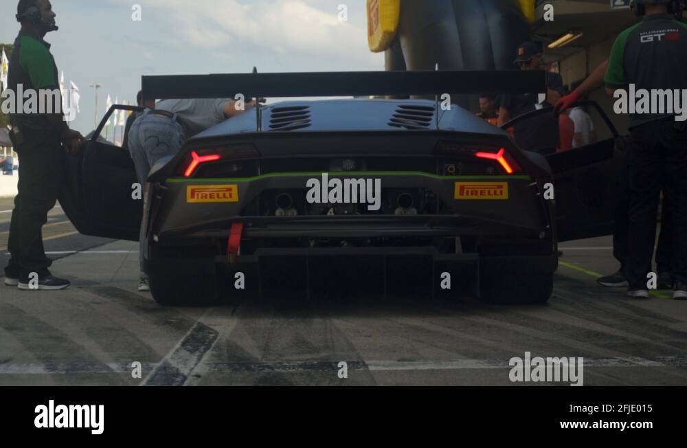 Back of an aggressive black race car with lights on at the pit stop ...
