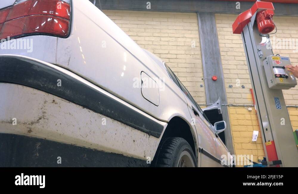 Mechanic doing inspection and service on car in garage. Side view of ...
