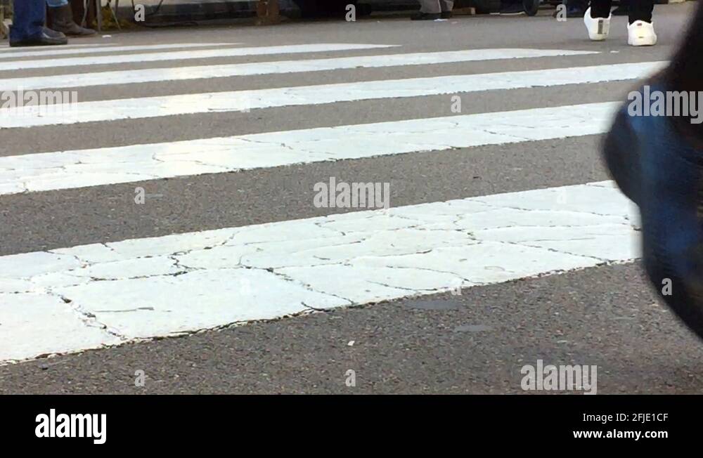 A view of a pedestrian crossing in a crosswalk and some people passing ...